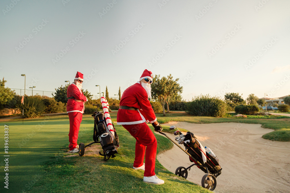 Two Santa Claus with golf bags.on the golf course Stock-Foto | Adobe Stock