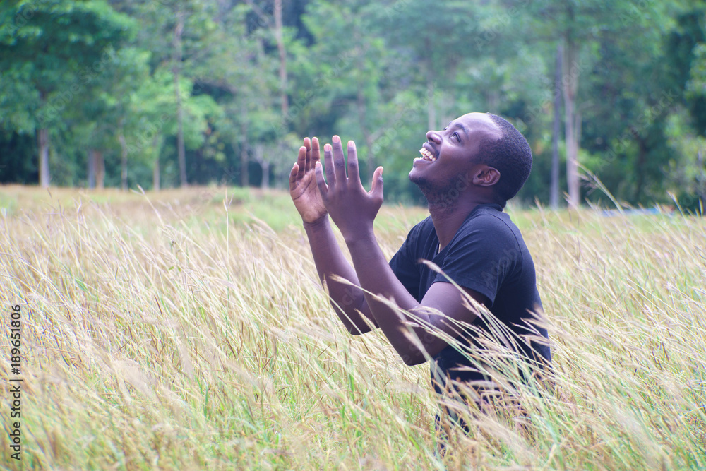 African man praying for thank god with light flare in nature. Stock ...