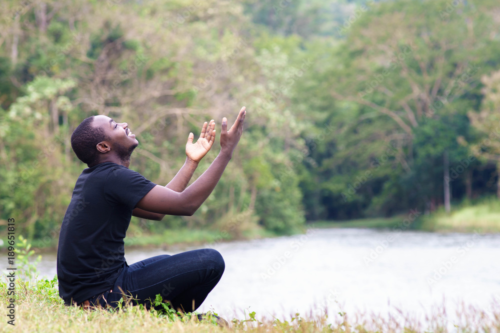 African man praying for thank god with light flare in nature. Stock ...
