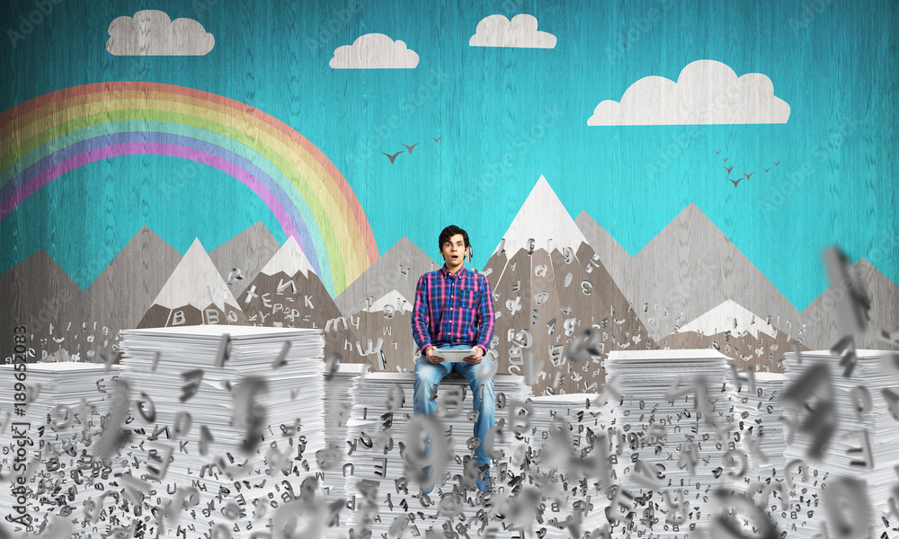 Young man sitting on pile of paper documents. Stock Photo | Adobe Stock