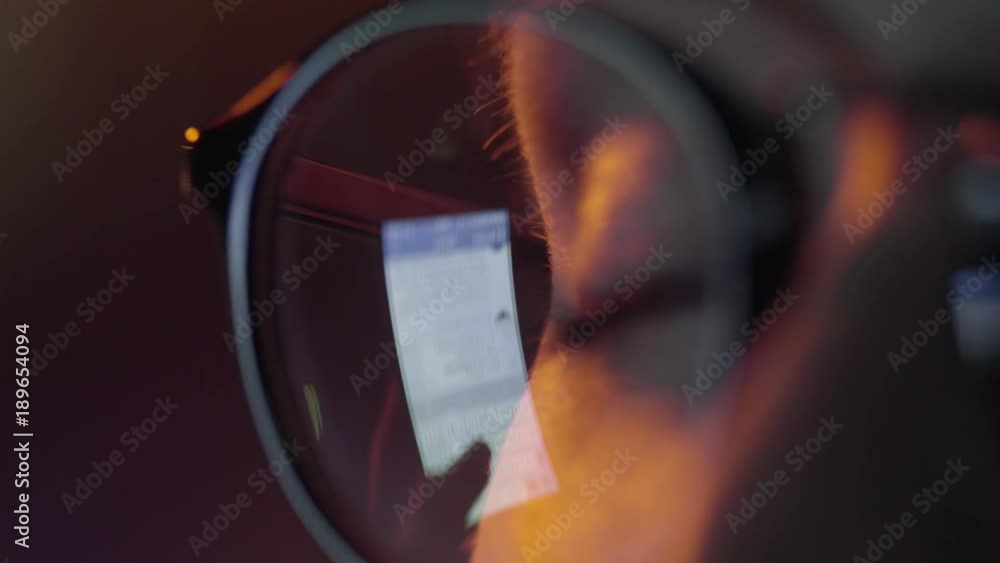 Close up of glasses with the reflection of phone in it. A young woman ...