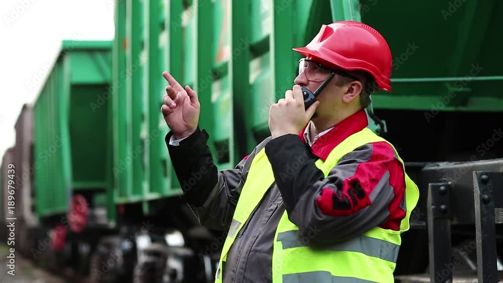 Railway worker with portable radio transmitter near goods trains ...