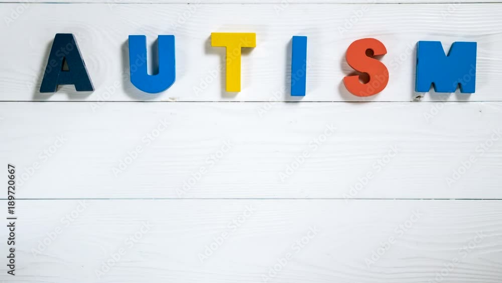 Word AUTISM and hand with a piece of puzzle on white wooden background ...