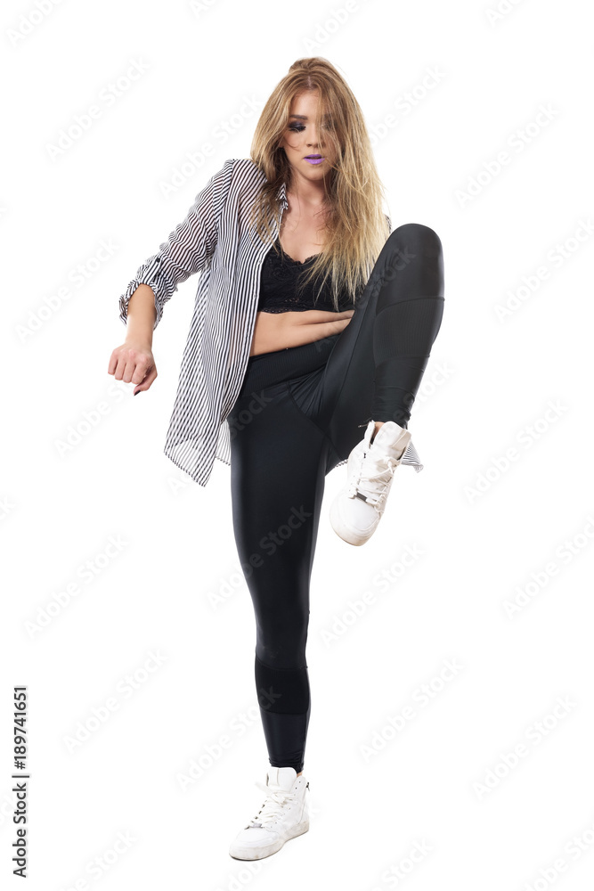 Mid air action pose of energetic female jazz dancer raising leg with ...