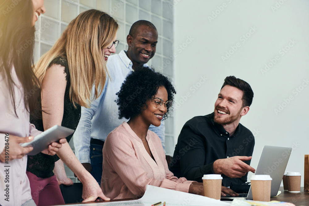 Smiling colleagues working together around a desk in an office Stock ...