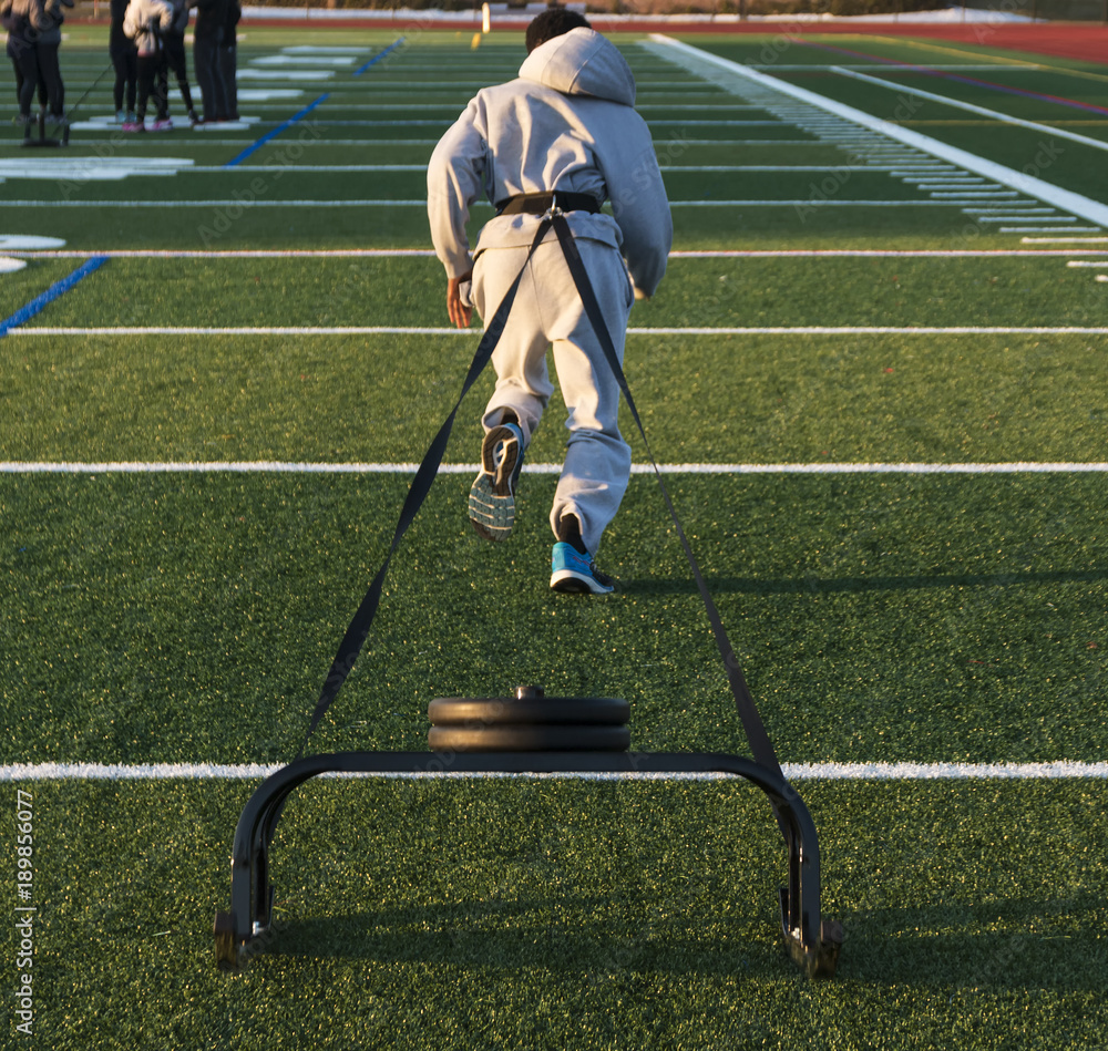 Runner pulling a sled with weights on a turf field Stock Photo | Adobe ...
