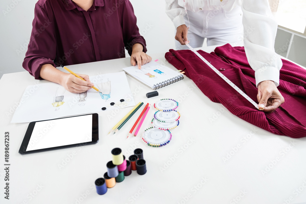 Two young professional Fashion designer colleagues working and project ...
