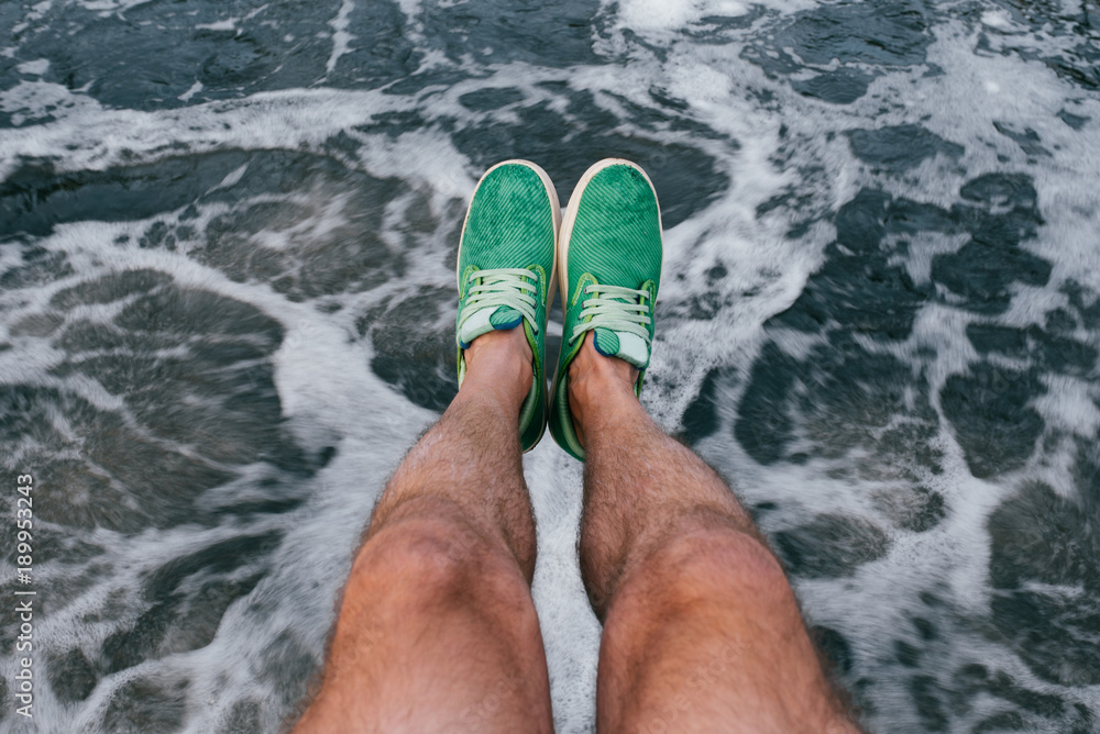 Tanned hairy strong male legs in green summer lightweight sneakers ...
