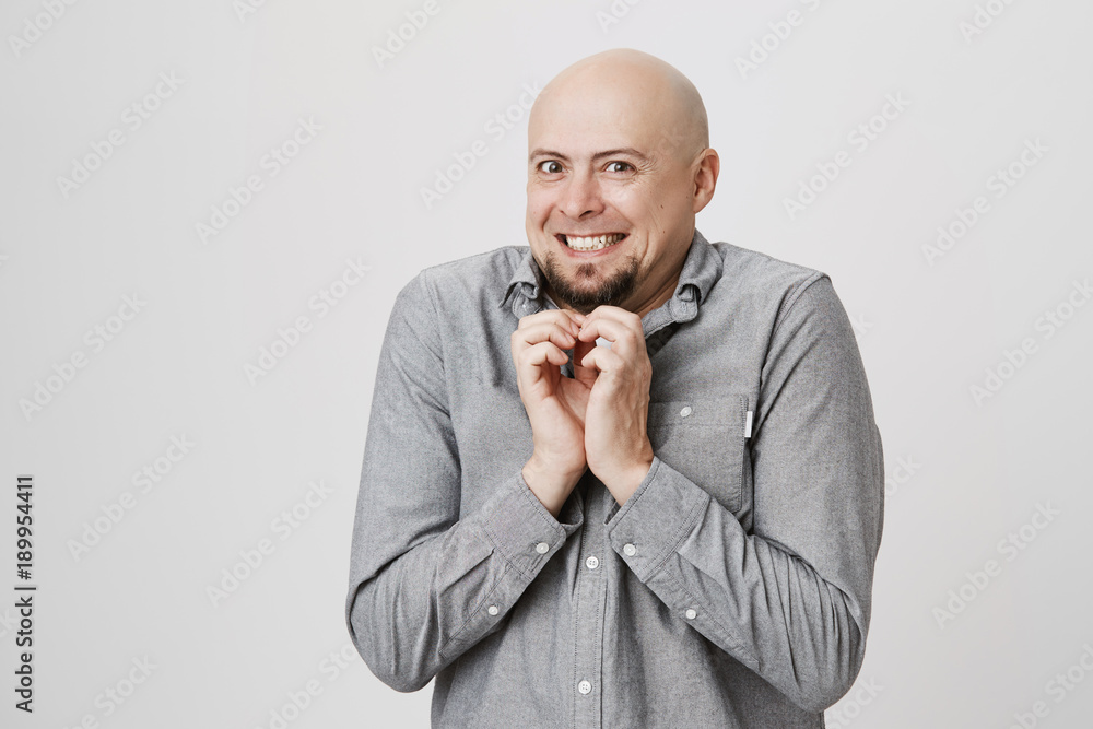 Horizontal portrait of bald bearded man in gray shirt poses against ...