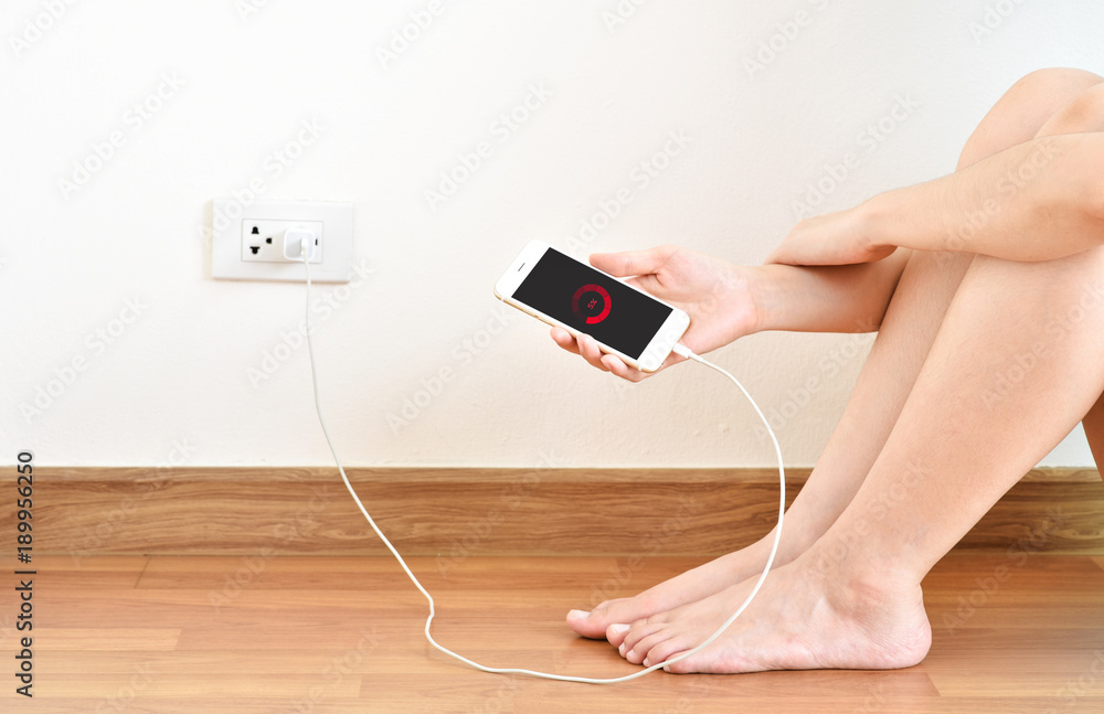 Girl using mobile phone while charging the battery Stock Photo | Adobe ...