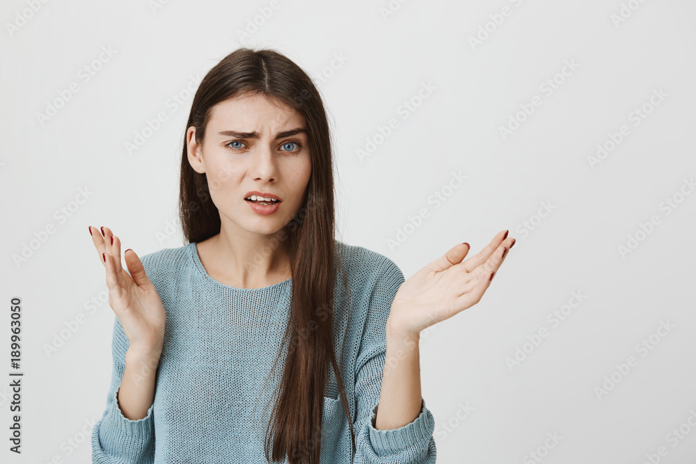 Headshot of clueless young caucasian brunette woman looking at camera ...