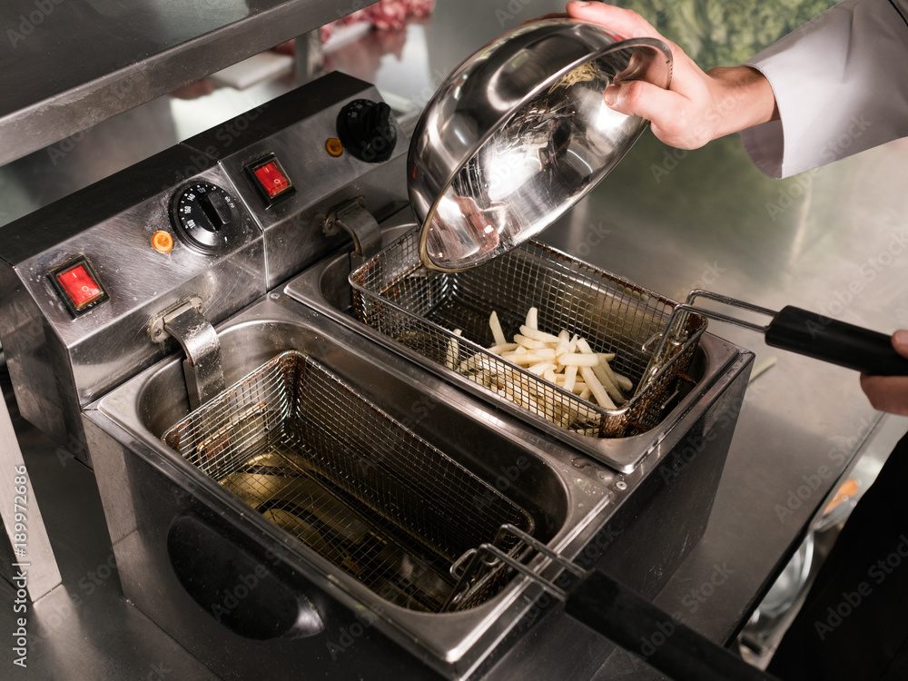 French fries - best junk food ever. Cook preparing fast food in the ...