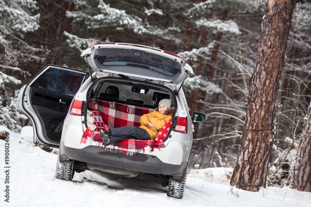 Smiling child laying inside of car back boot for luggage. Winter ...