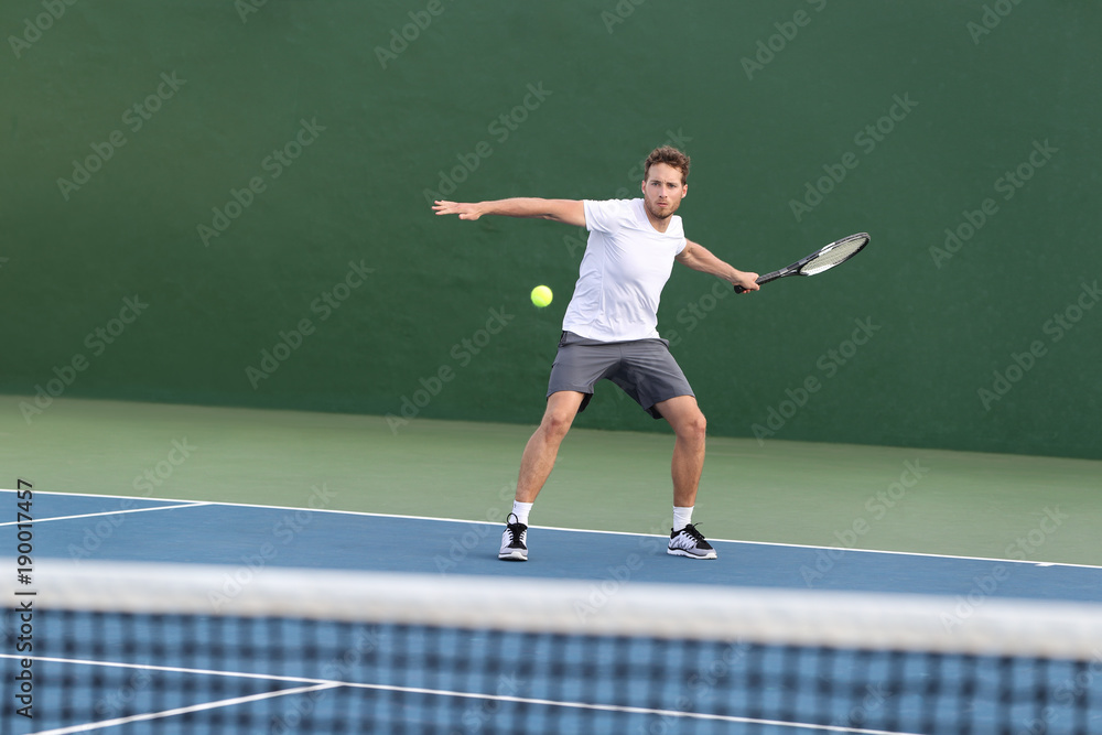 Professional tennis player athlete man focused on hitting ball over net ...