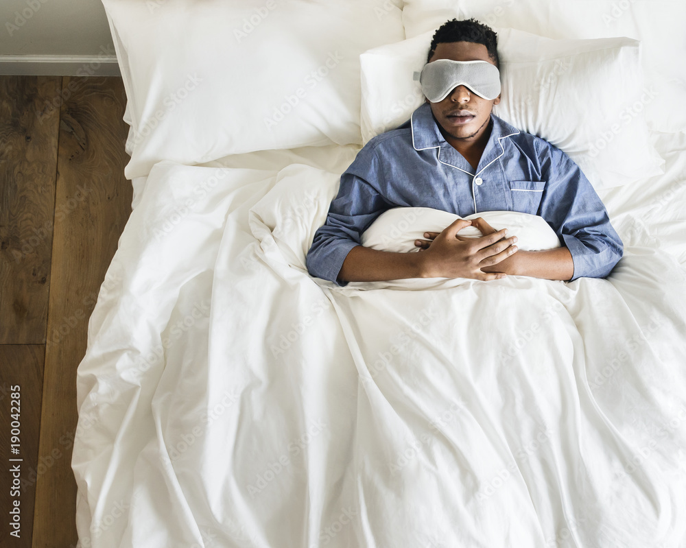 Black man sleeping on bed with eye mask Stock Photo | Adobe Stock