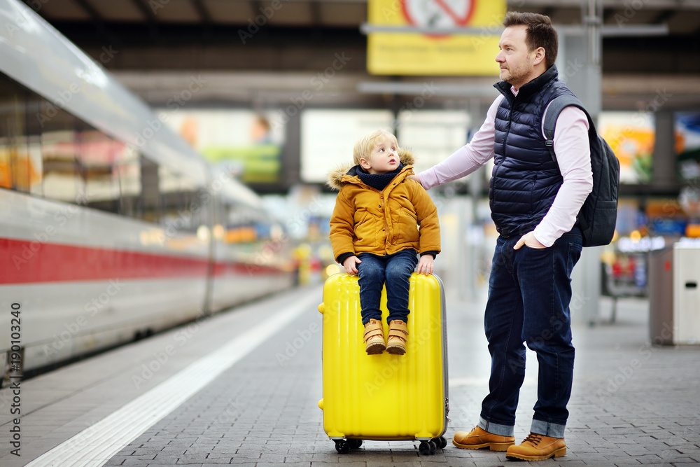 Cute little boy and his father waiting express train on railway station ...