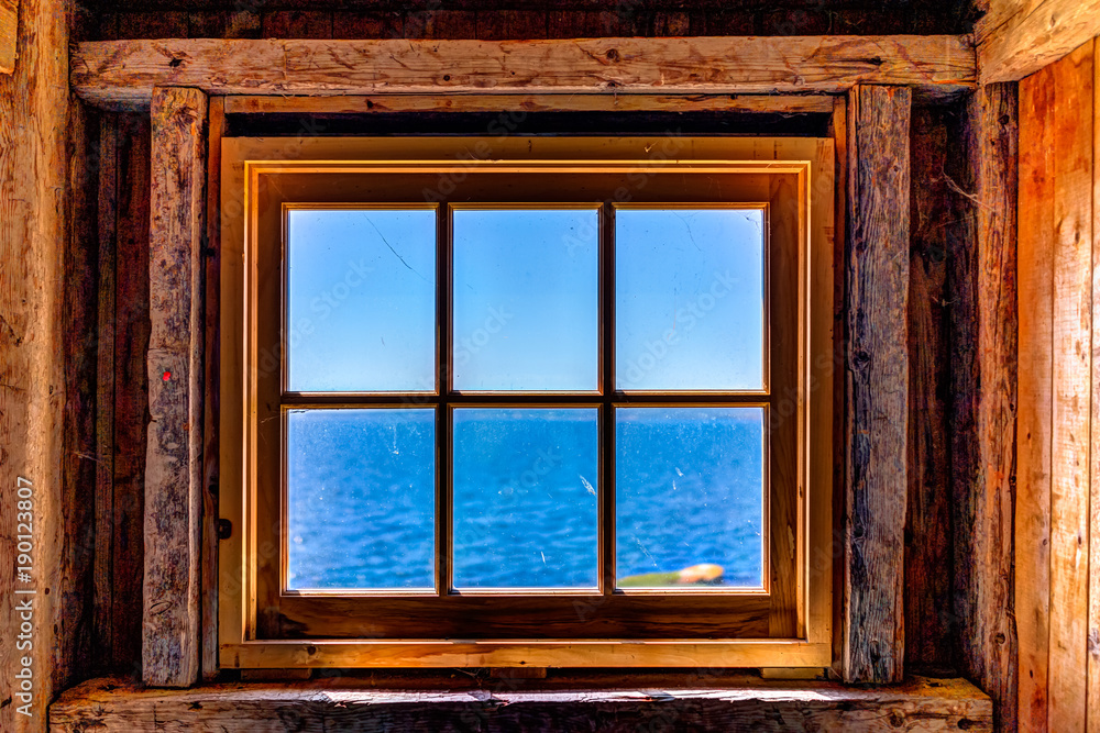 Looking through old rustic window of house with ocean view in ...
