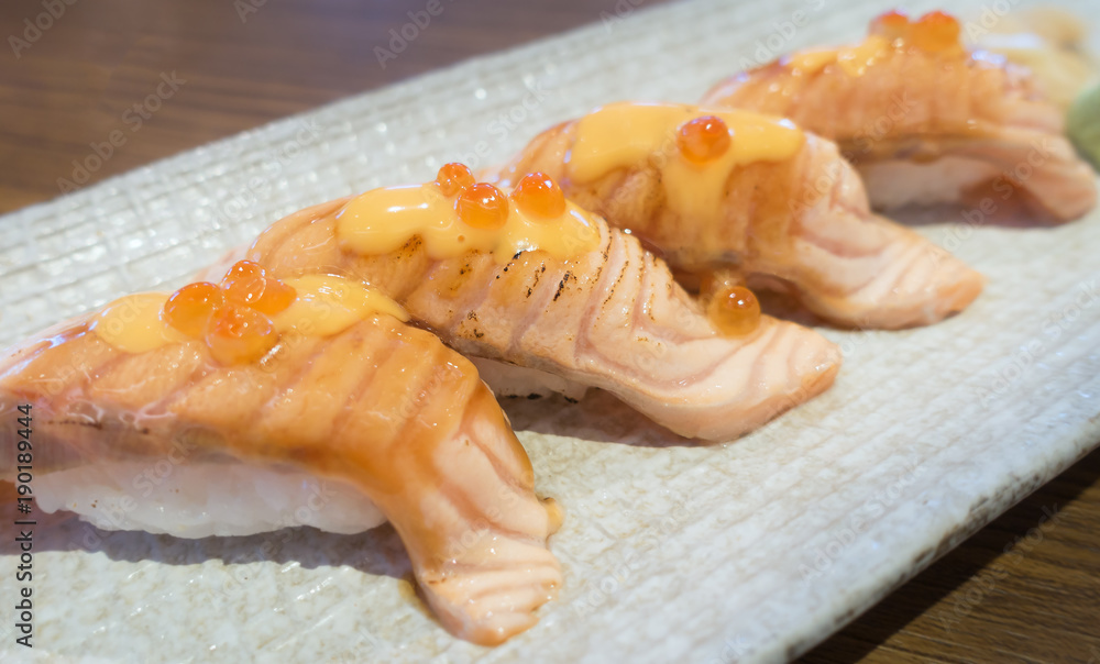 Closeup of salmon aburi sushi topped with saikyo sauce on plate, Aburi ...
