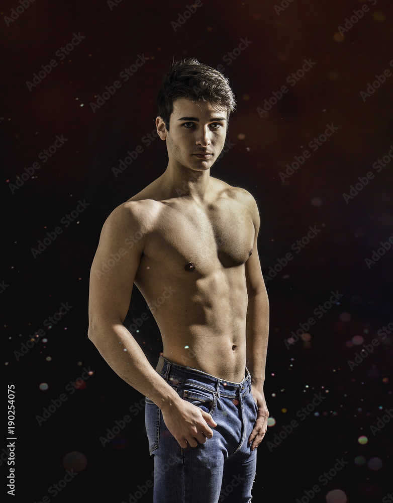 Handsome, fit muscular young man shirtless, wearing only jeans standing ...