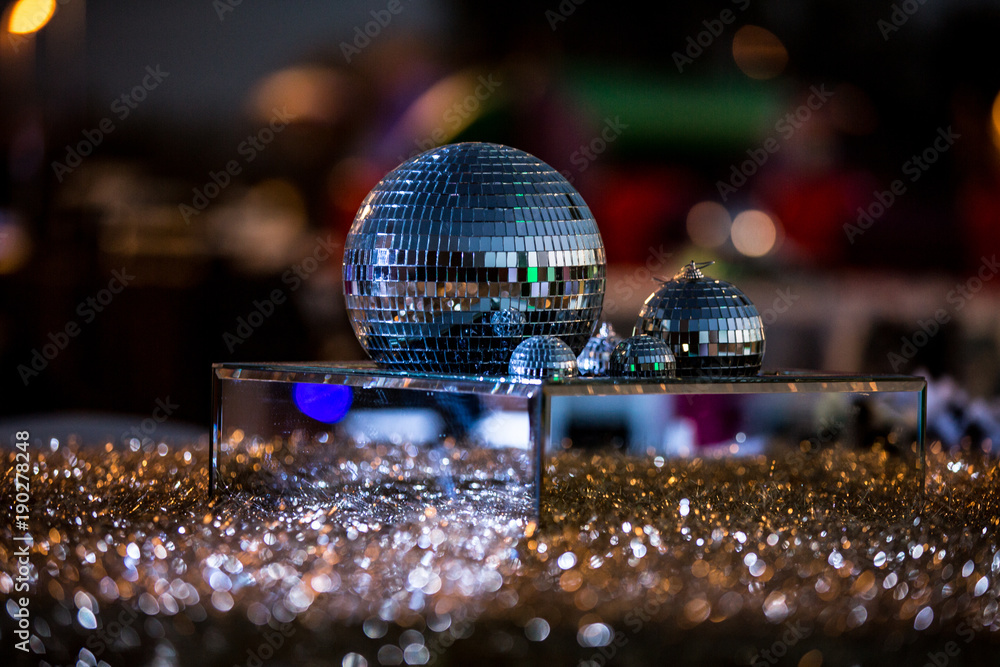 Mirrored disco balls on top of mirrored platform surrounded by glitter ...
