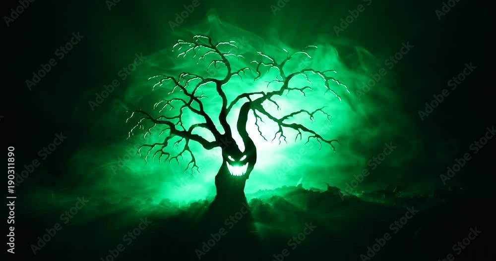 Silhouette of scary Halloween tree with horror face on dark foggy toned ...