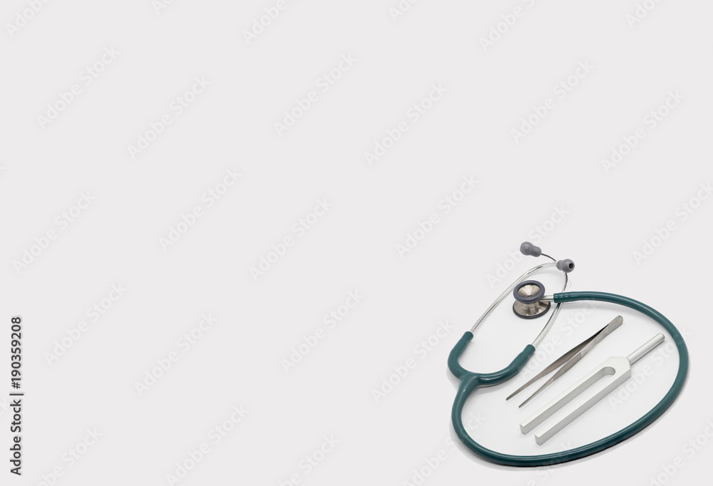 green stethoscope and doctor tools tuning fork forceps on isolated ...