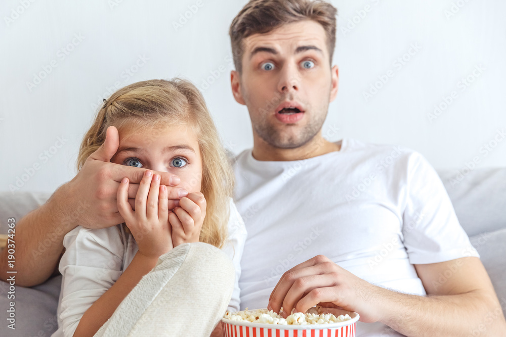 scared father and daughter watching horror movie at home Stock Photo ...