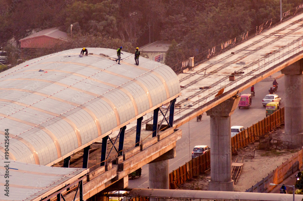 Construction workers standing on the roof of a metro station and making ...