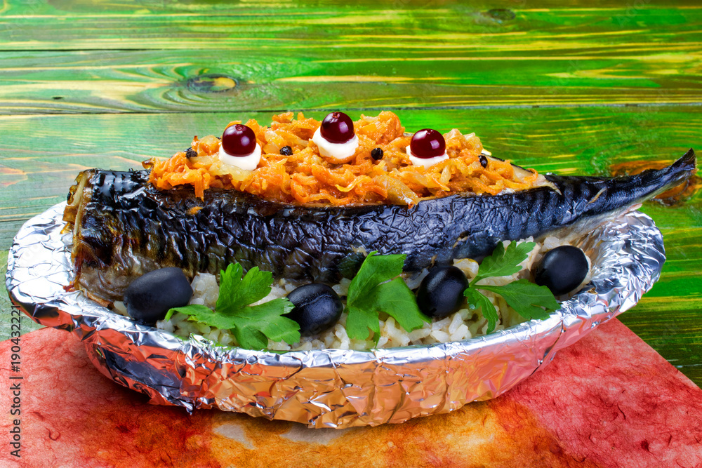 Baked mackerel fish stuffed with carrots, olives, parsley lies on a ...