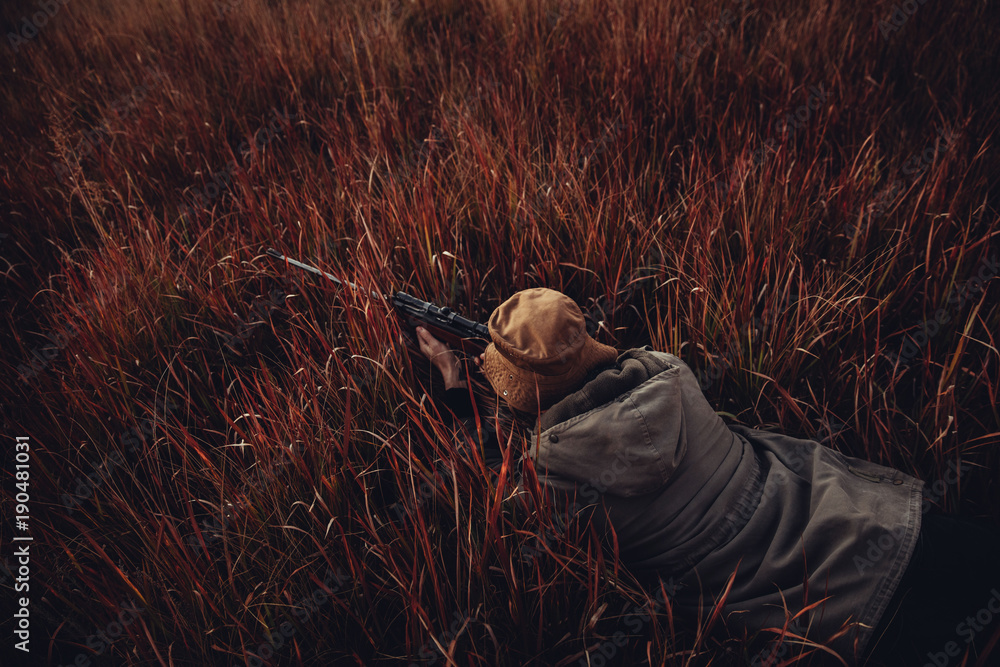 Hunter laying in high grass with rifle aiming on prey Stock Photo ...