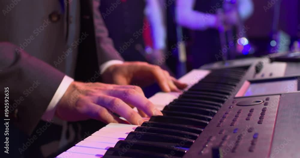 Man in smart suit plays electric keyboard with brass section in ...