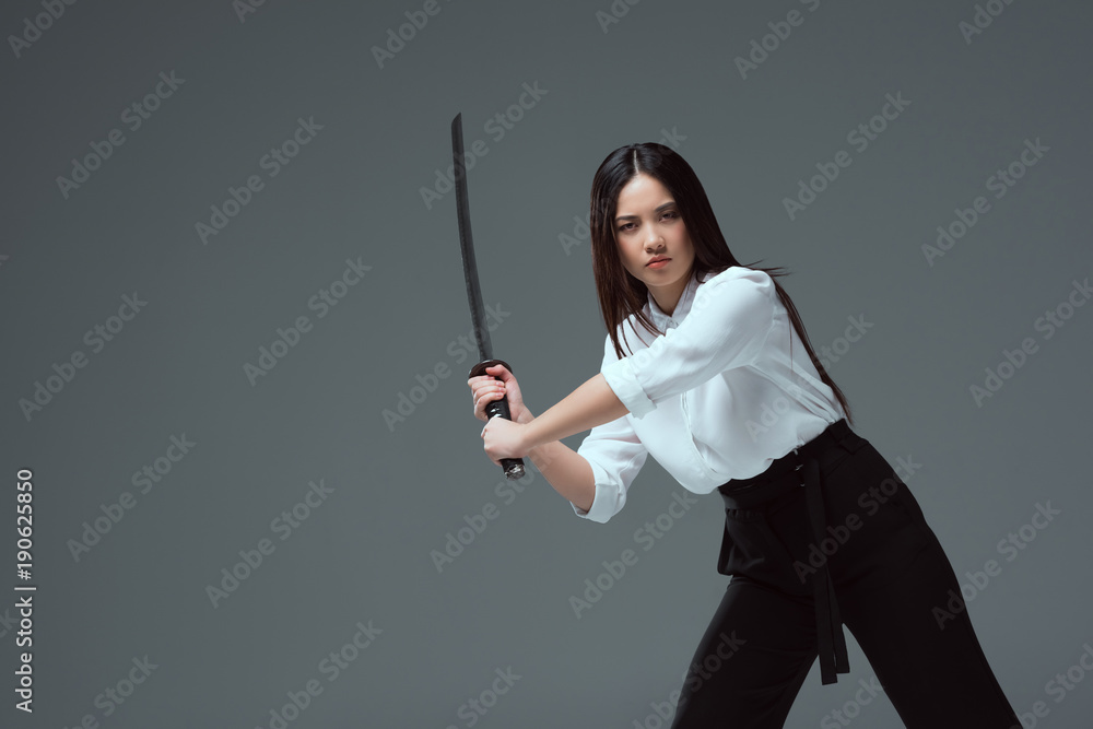 young asian woman fighting with katana sword and looking at camera ...
