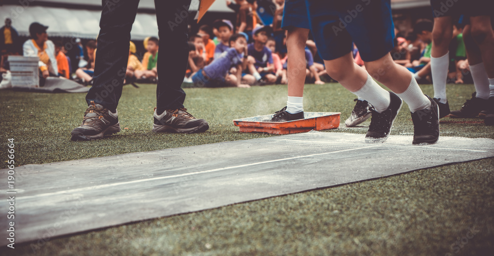 Students boy taking long jump on rubber board during a school sport ...