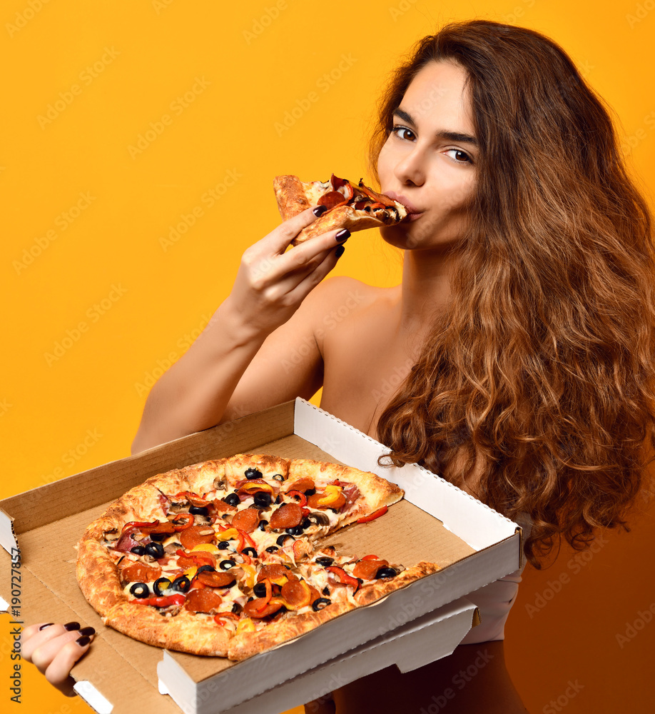 Young beautiful woman eat pepperoni pizza slice and hold whole pizza in ...