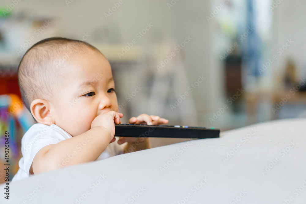 Happy smiling 10 month baby boy holding a remote control tv.child ...