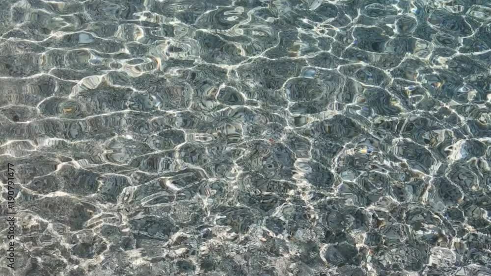 Paradise sea ripple water surface with sunlight glow and pebble bottom ...