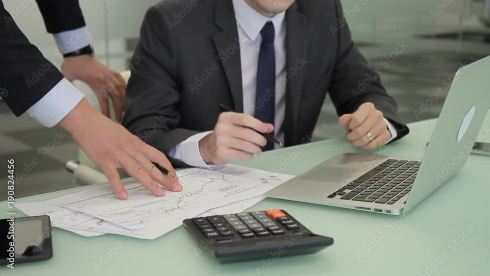 A pair of brokers compare the exchange rates charts on the paper with ...