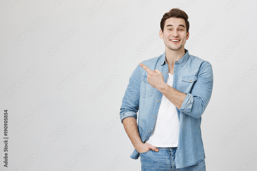 Studio portrait of attractive european man in denim glothes, pointing ...