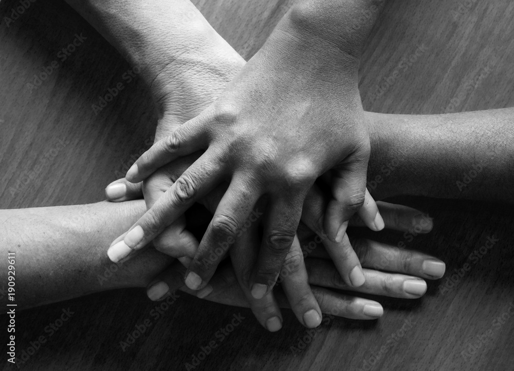 looking down on four hands placed ontop of each other, the top hand and ...