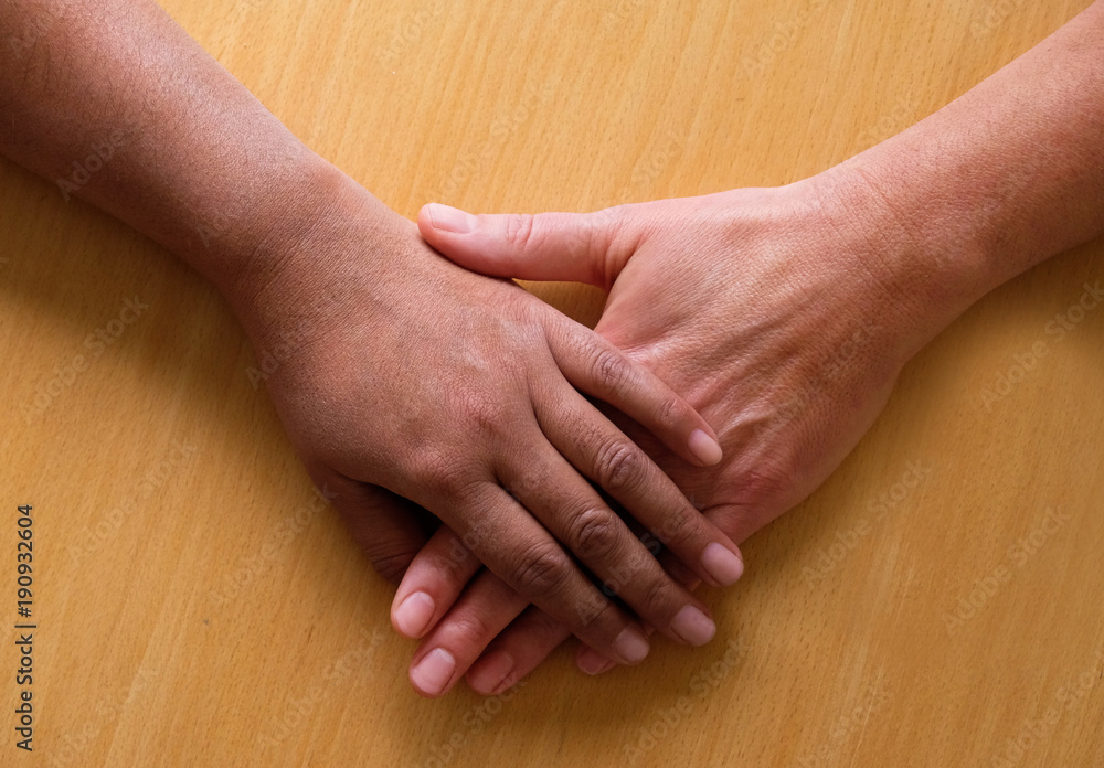 overhead view point of two hands and lower arms placed ontop of each ...