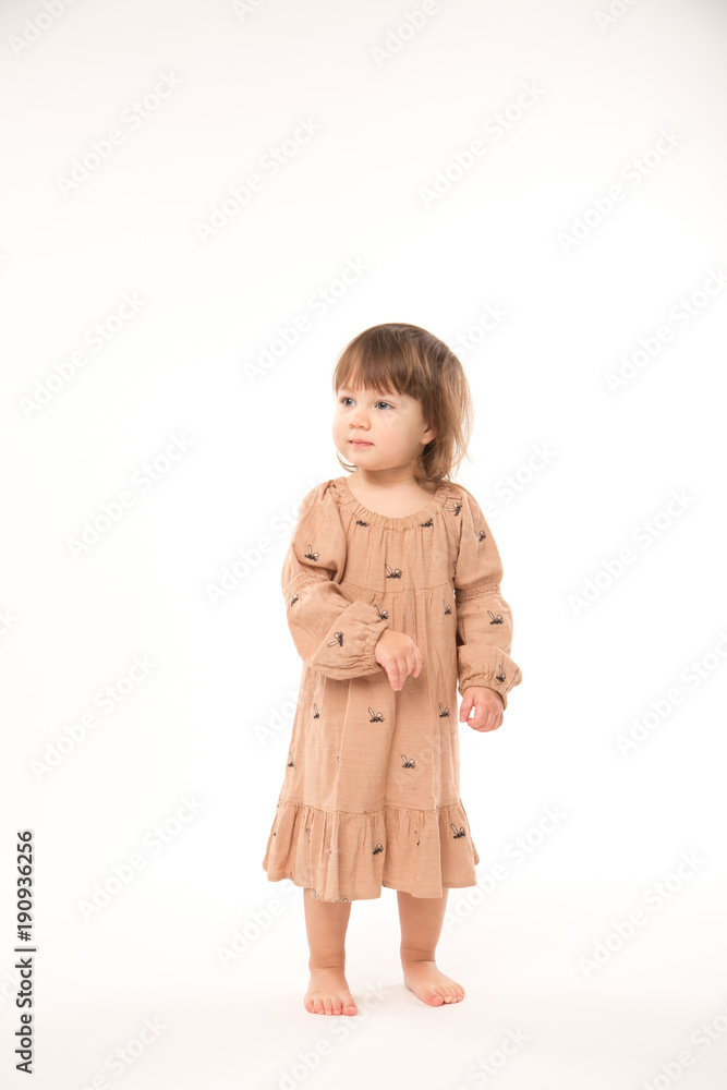 Cute little girl in beige dress isolated on white background. Portrait ...