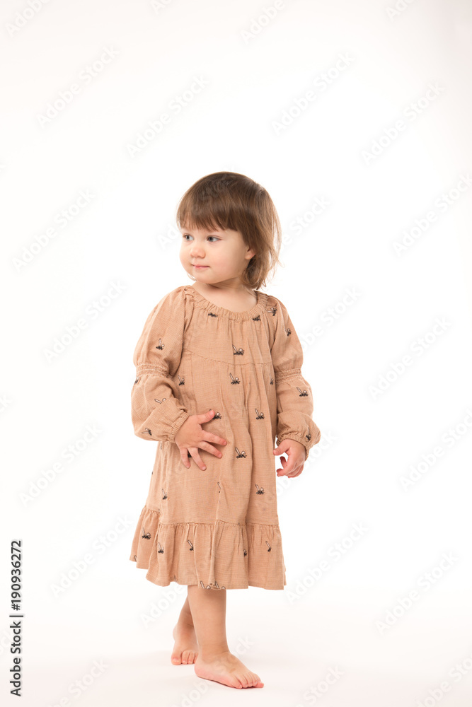 Cute little girl in beige dress isolated on white background. Portrait ...