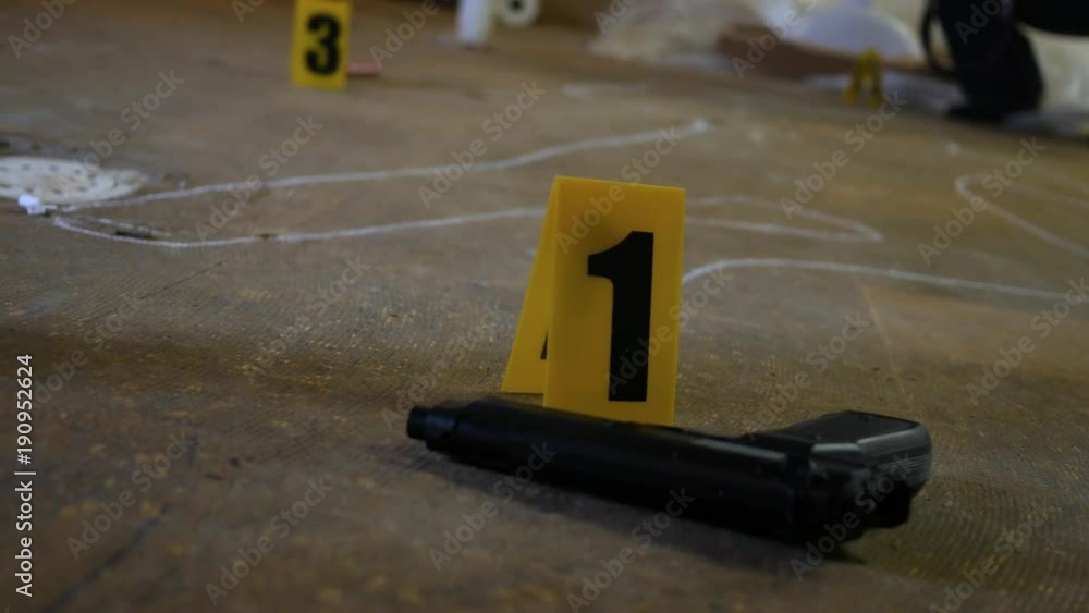 Cinematic camera move past 9mm handgun with evidence marker at active ...