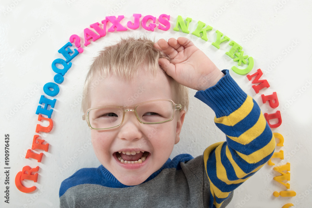 Happy charming Caucasian blond kid in colored clothes playing with ...