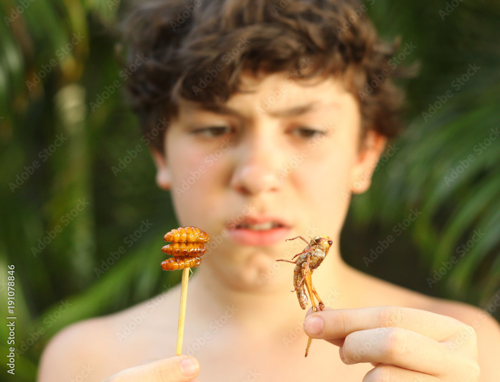 teenager boy with disgust grimace hold unusial strange thai food ...