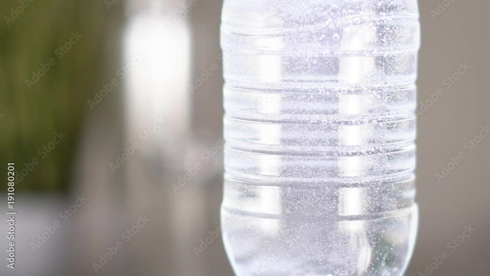 Slow motion. Gas bubbles float in a plastic bottle with drinking water ...