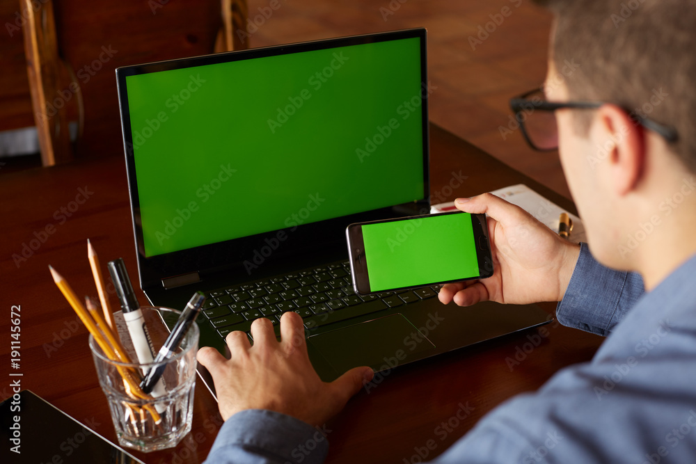 Back view of businessman using smartphone and laptop typing in office ...