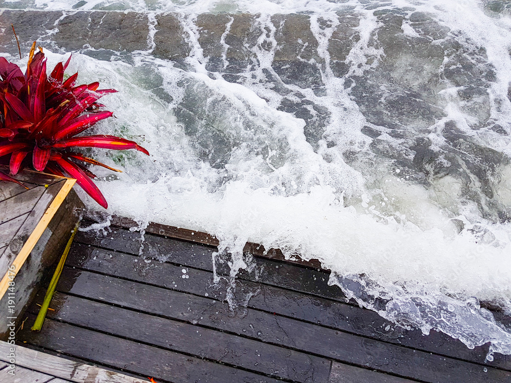 rising sea effects of climate change as water washes over seawall ...