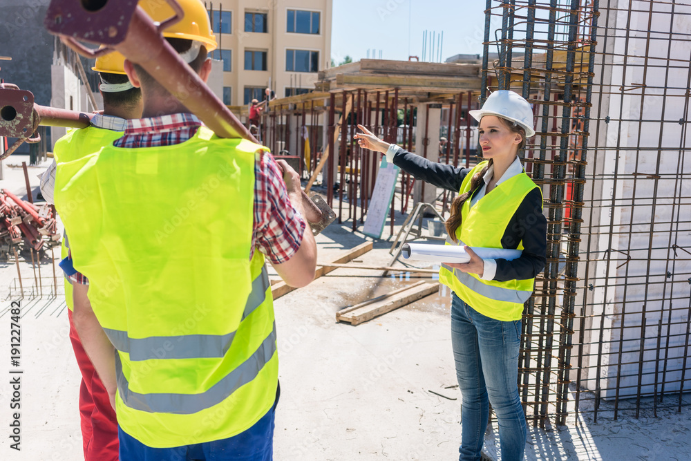 Experienced female foreman coordinating and guiding workers by showing ...