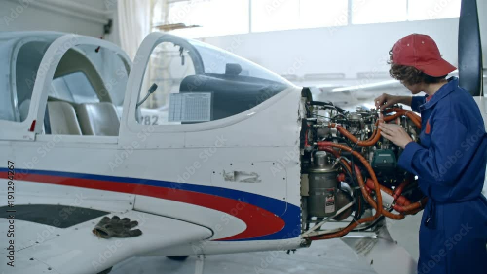 Tracking shot of young female aircraft mechanic repairing airplane ...